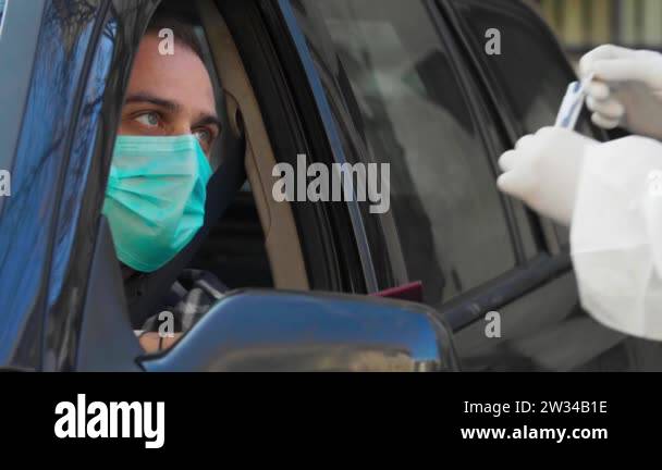 Medical worker performing drive-thru COVID-19 test, taking nasal swab ...