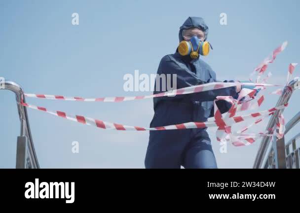 Man in chemical suit tearing off caution tape and leaving. Portrait of ...