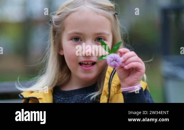 Portrait of a lovely little girl holds a clover flower in his hands ...