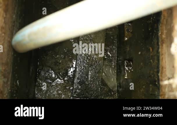 Septic cesspool emptying pumping into pipe tank by suction hose under ...