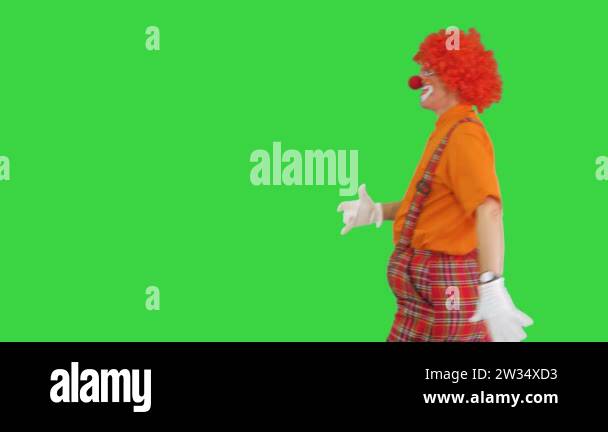 Clown walking in and saying hello waving his hand to camera on a Green ...