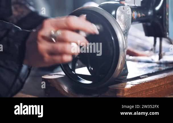 Close-up of woman's hand spinning the metal wheel of an old sewing ...