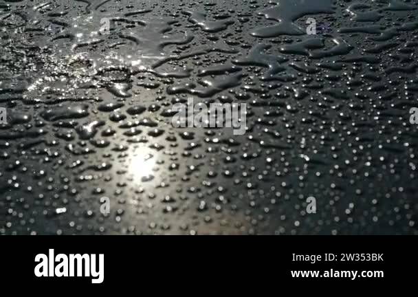 Light rain dripping on a shiny smooth floor with small formed puddles ...