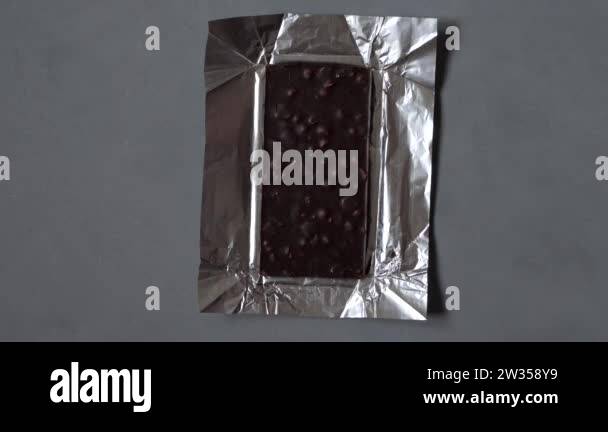 chocolate bar is unpacked, divided into slices and eaten. Foil ...