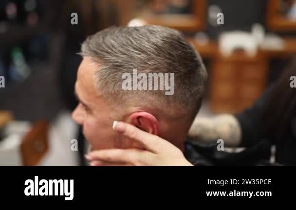 Hairdresser woman adds final touches to a haircut and taking off salon ...