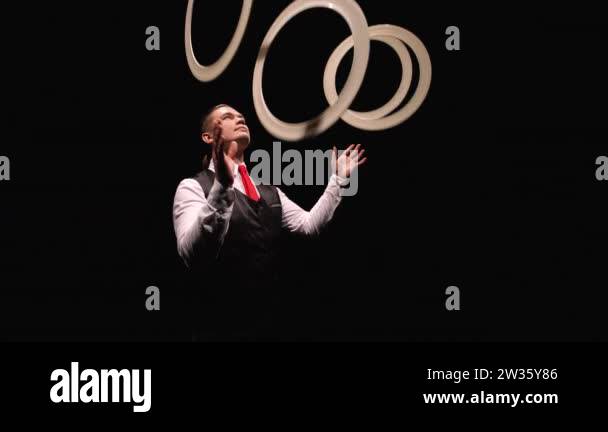 Camera rotates around concentrated man juggling white rings, then puts ...