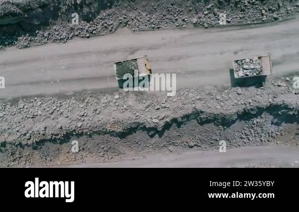 Mining dump trucks in large granite open pit mine. Loaded trucks rides ...