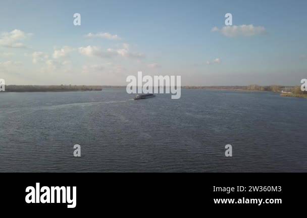 A tugboat ship pushes a barge upstream of the river to transport bulk ...