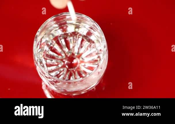 An effervescent tablet dissolves in a transparent glass with water on a ...