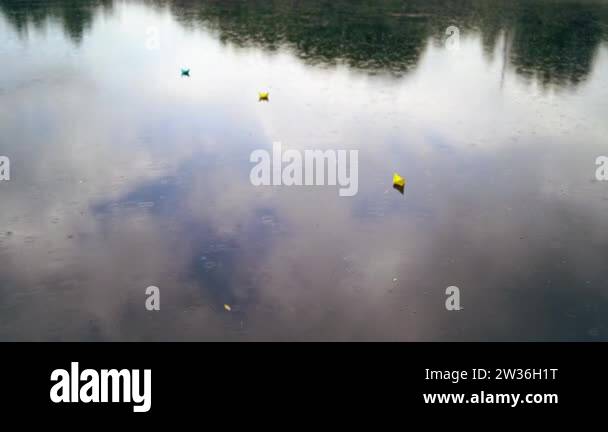 Three colorful paper ships on water under the rain. Handmade origami ...