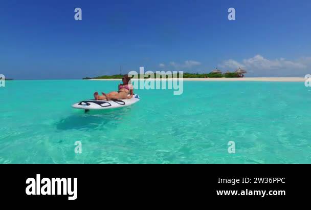 video of the athletic tan girl lying on the surfboard and swinging on ...