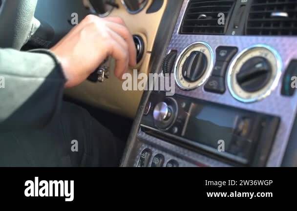 Man putting his car keys into socket and starting the engine. Man hand ...