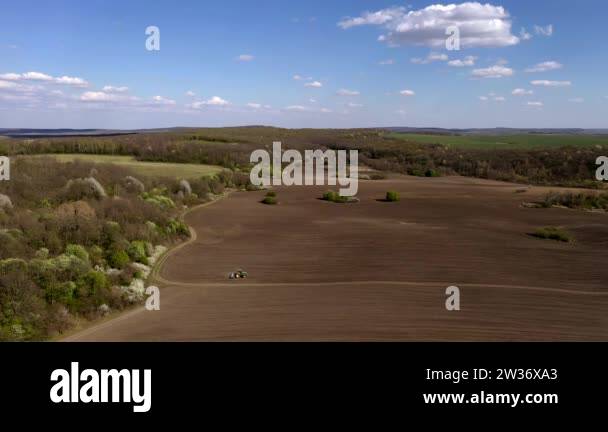 Aerial view large tractor cultivating a dry field. Top down aerial view ...