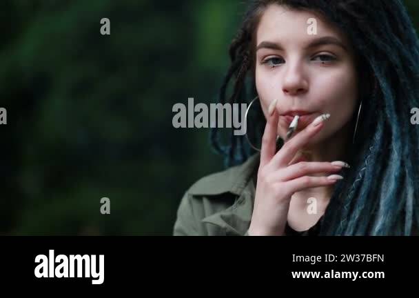 Woman Smoking Cannabis at Sunset, Close Up. The woman rolled the joint from fresh marijuana weed ...