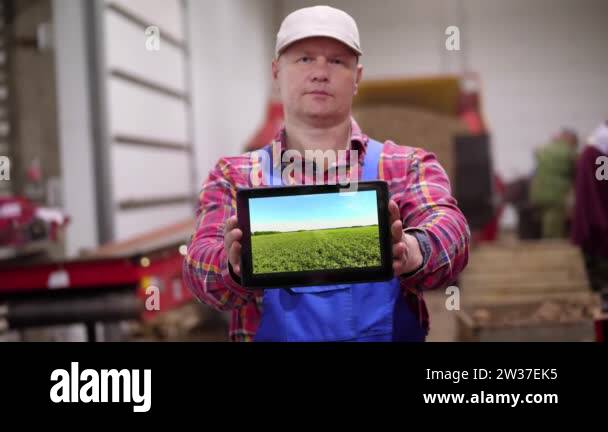 in potato storage warehouse, farmer holding digital tablet in his hands ...