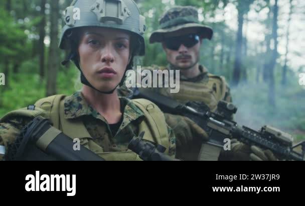 Squad of soldiers patrolling across the forest area, team with male and ...