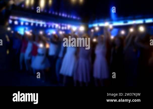 People wave their arms and hold light from flashlights in a nightclub ...