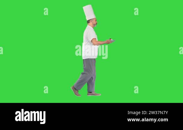 Male pastry chef walking fast with dessert in his hands on a Green ...