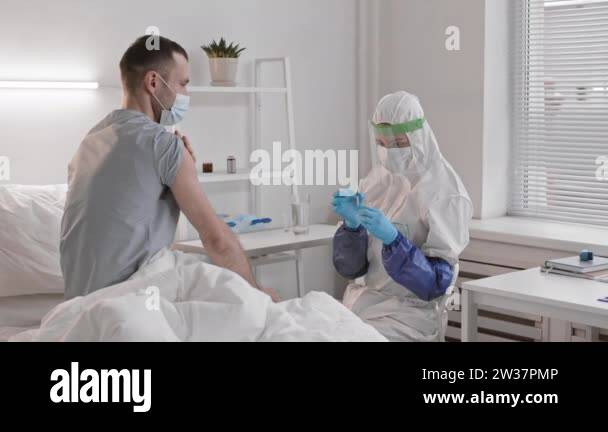 Medium long of medical worker wearing full coverage hazmat suit sitting ...