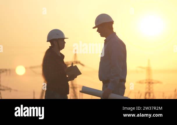 Engineers man and woman work on the field with electric towers at ...