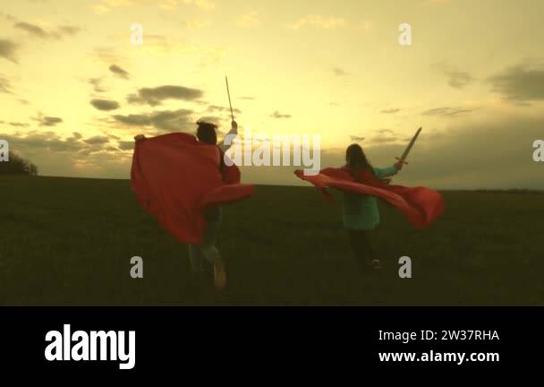 girls in red cloaks run with swords in hand across field playing ...