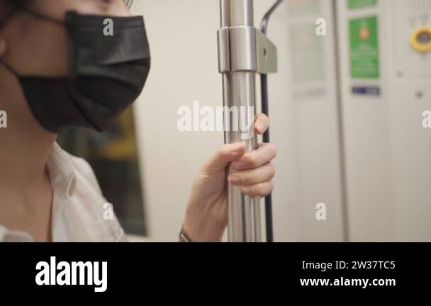 Young asian woman in black protective mask, hold on to the pole ...