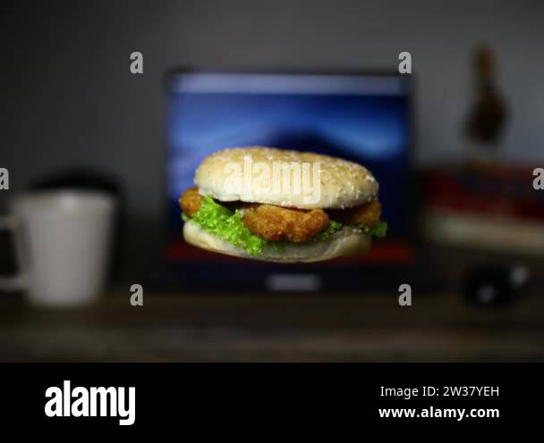 Seamless footage of a burger spinning around in front of laptop. Order ...