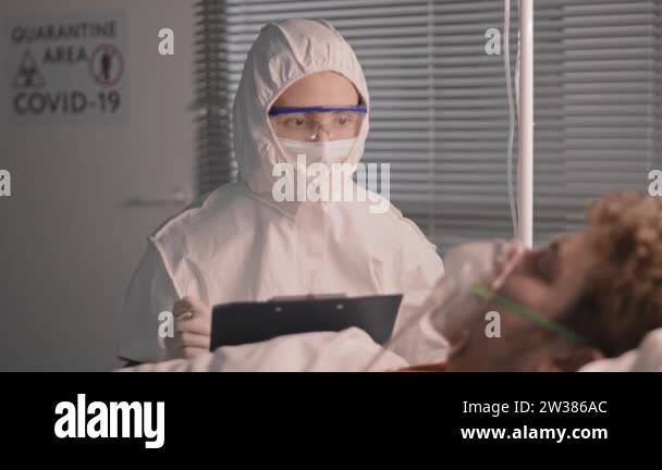 Chest-up of brown-eyed Caucasian doctor in hazmat suit standing near ...