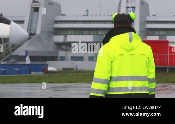Airport supervisor wearing a protective medical mask stands on the runway. Aviation staff back ...
