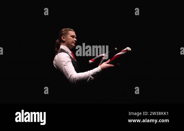Orbital shot of a stylish man juggling with pins. The juggler hones his ...