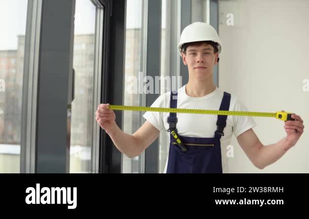 The window installer measures the dimensions of the window frame with a ...
