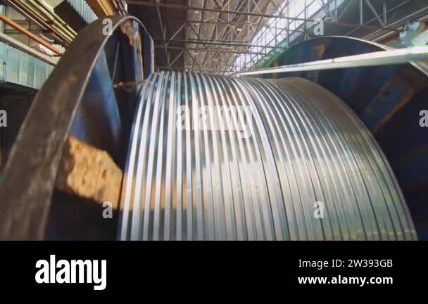 A huge bobbin unwinds a wire in a cable factory. Products are used in ...