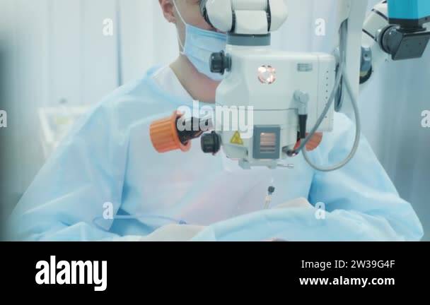 Surgeon looking into the microscope at the eye of female patient at the ...