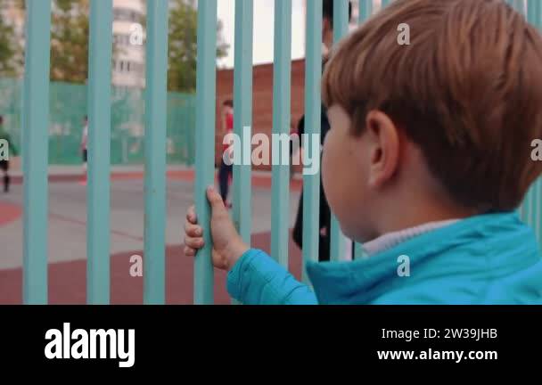 A sad little boy watching another kids playing football behind the ...