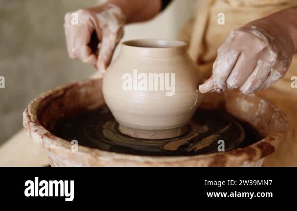 The female potter cuts the base of the vase with a fishing line and ...