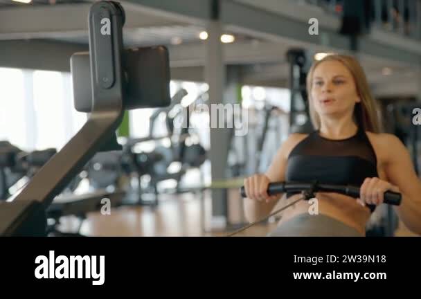 woman pulling weight on sports trainer in fitness club. fit girl doing ...