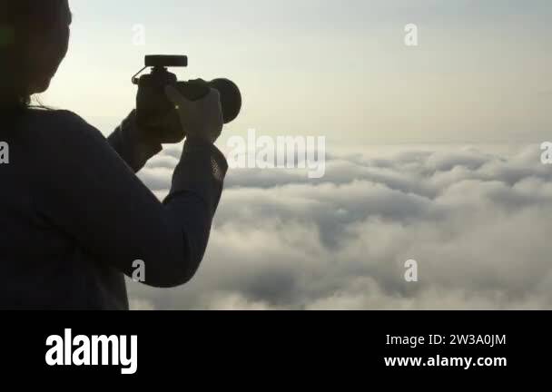 Rear view of woman photographer is taking images with dslr camera in ...