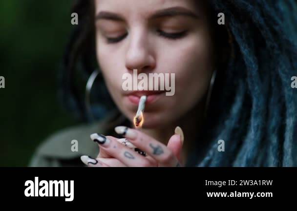 Woman Smoking Cannabis at Sunset, Close Up. The woman rolled the joint ...