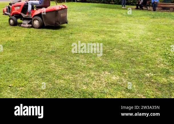 Lawn mowers with the mask cutting grass a green lawn with grass.Worker ...