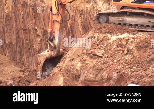 An excavator digs clay soil in a foundation pit to build a foundation ...