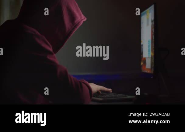 An unidentified man in the hood sits night for a computer monitor ...