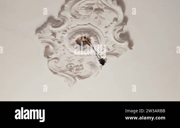 Old broken socket with hanging twisted wires on the apartment ceiling ...