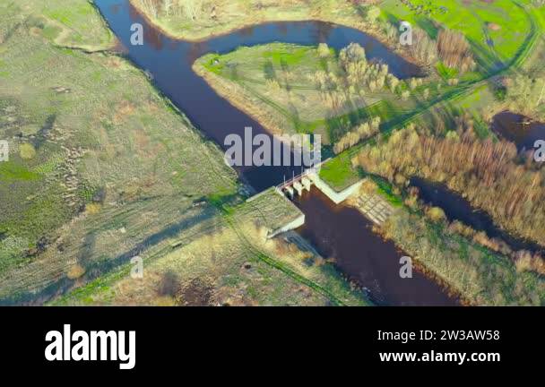 Small river with an open dam discharging water to prevent flooding and ...