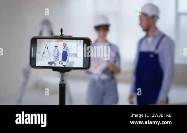 woman and man in helmet recording video on cell phone showing wall ...