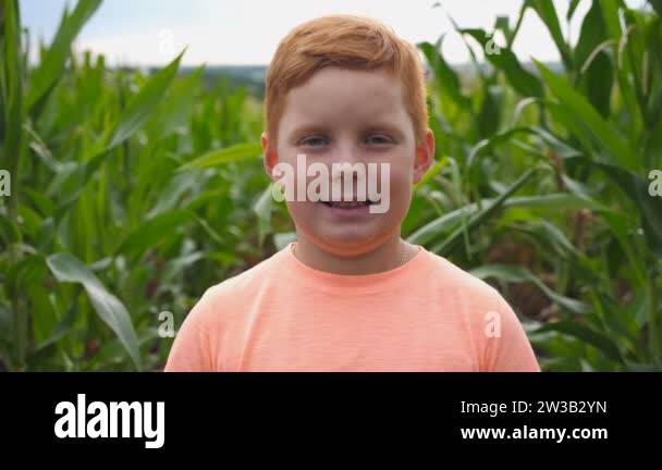 Close up of little smiling red-haired boy with freckles looking into ...