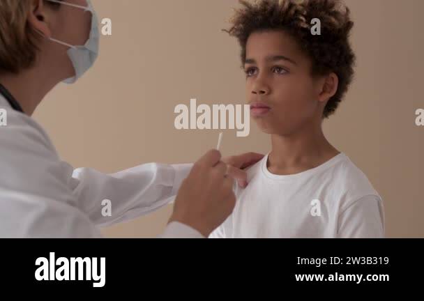 Female practitioner doctor takes nose swab of 10s patient. Little mixed ...