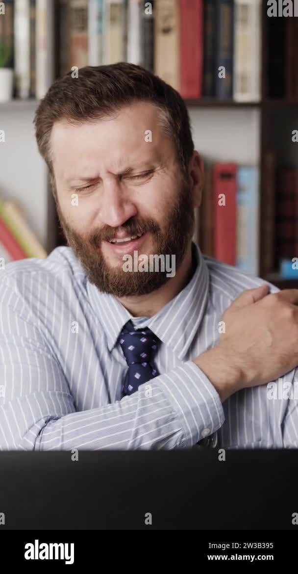 Shoulder pain. Vertical orientation man on workplace experiencing pain ...