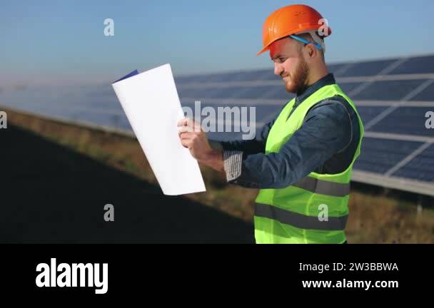 The engineer is looking at the project drawings. He is standing next to ...