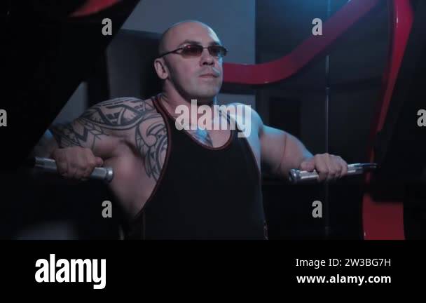 Professional bodybuilder trains pectoral muscles on the simulator in a ...