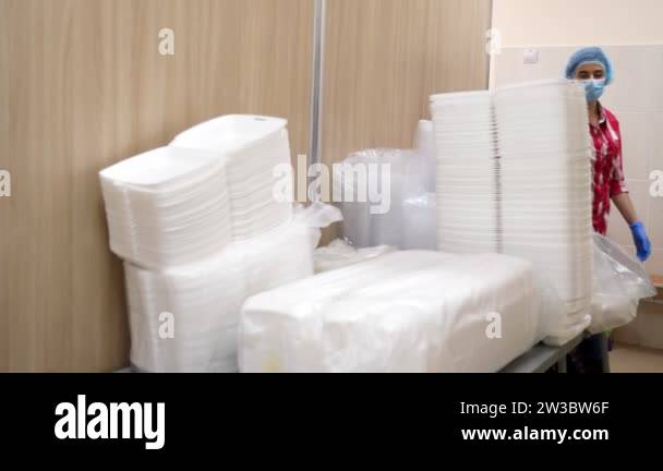 female volunteer takes plastic lunchboxes at storeroom in warehouse ...